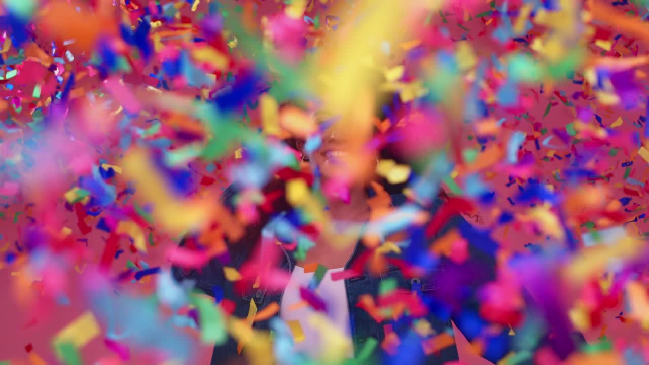Confetti falling down in slow motion, a yong smiling woman in the background enjoys the ...