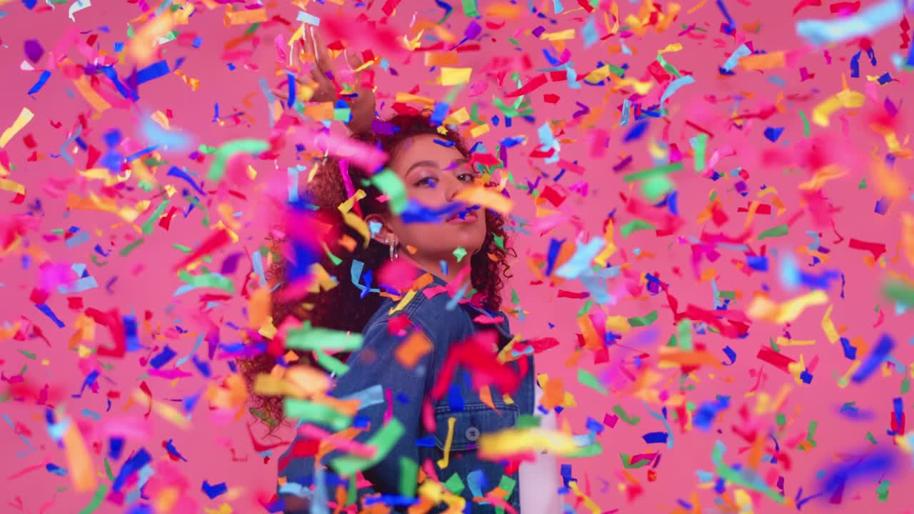 A young model strikes a heroic pose as multicolored confetti falls ...