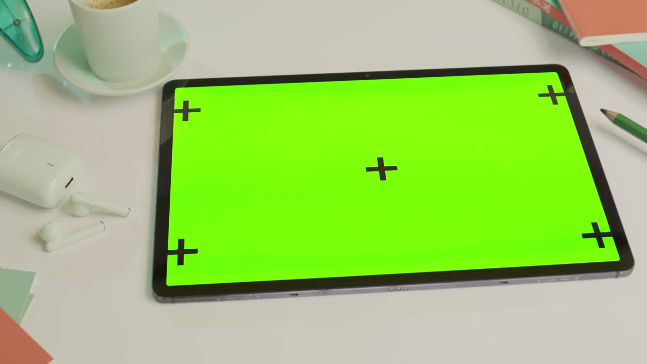 A sleek tablet featuring a green screen device sits on a desk ...