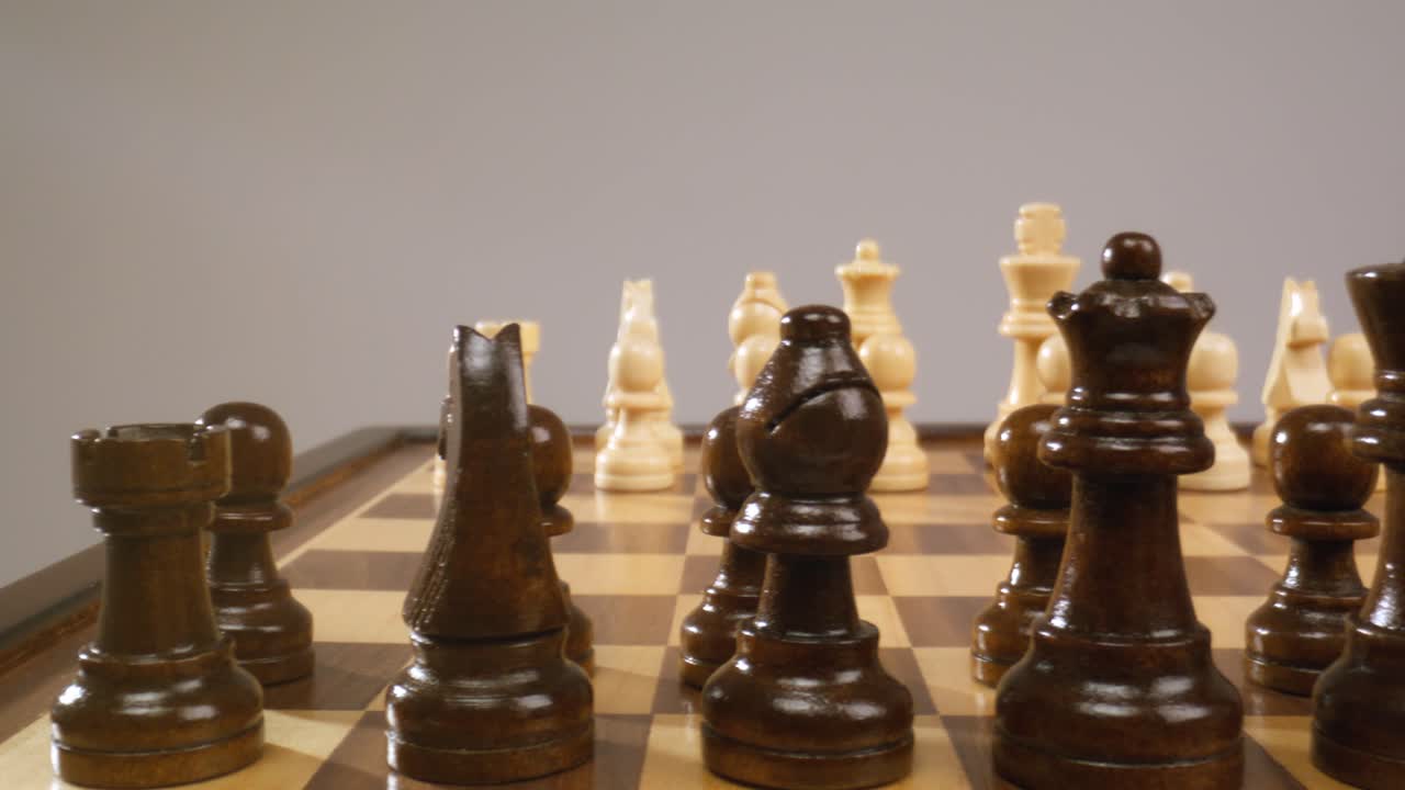 The camera glides close to the chess board pieces neatly arranged at ...