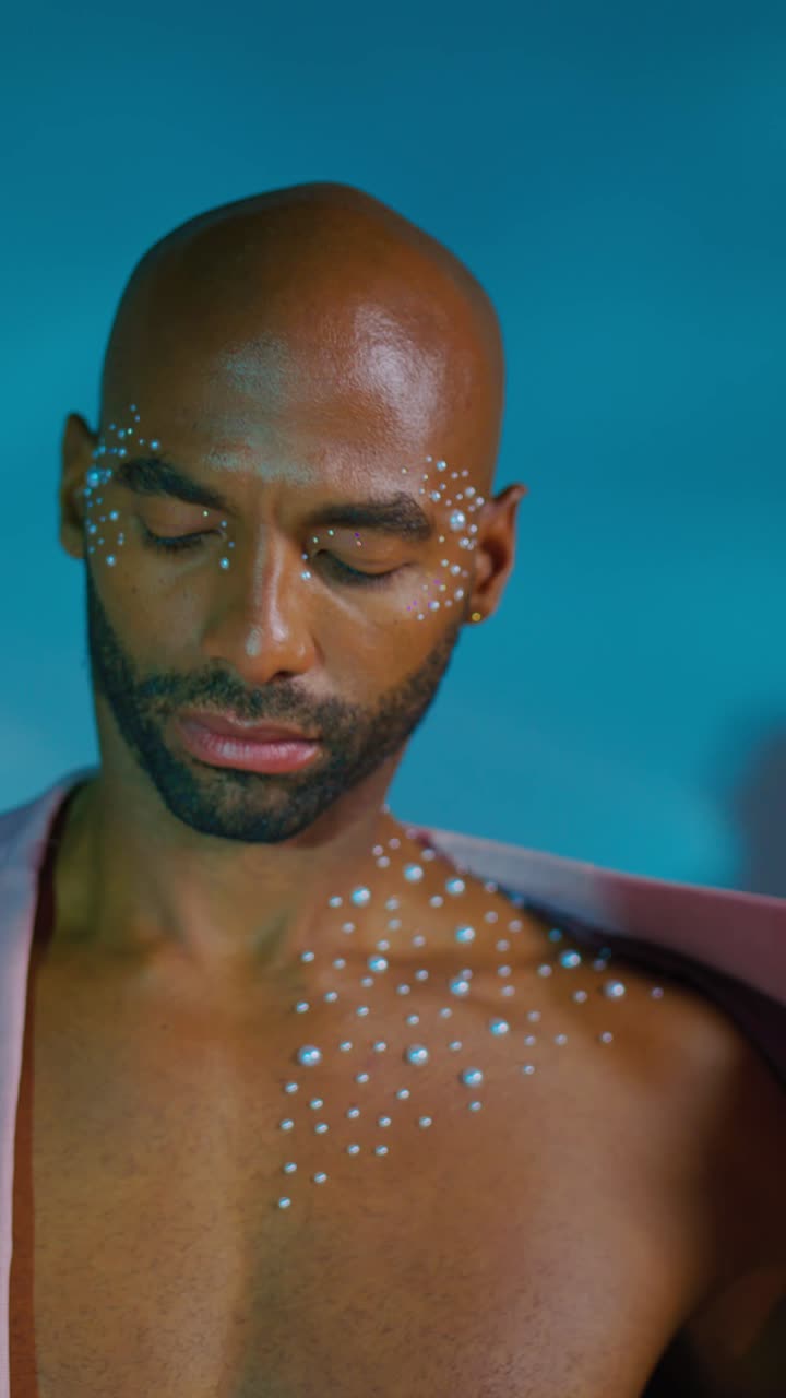 Man with glitter on face against blue background - Free Stock Video
