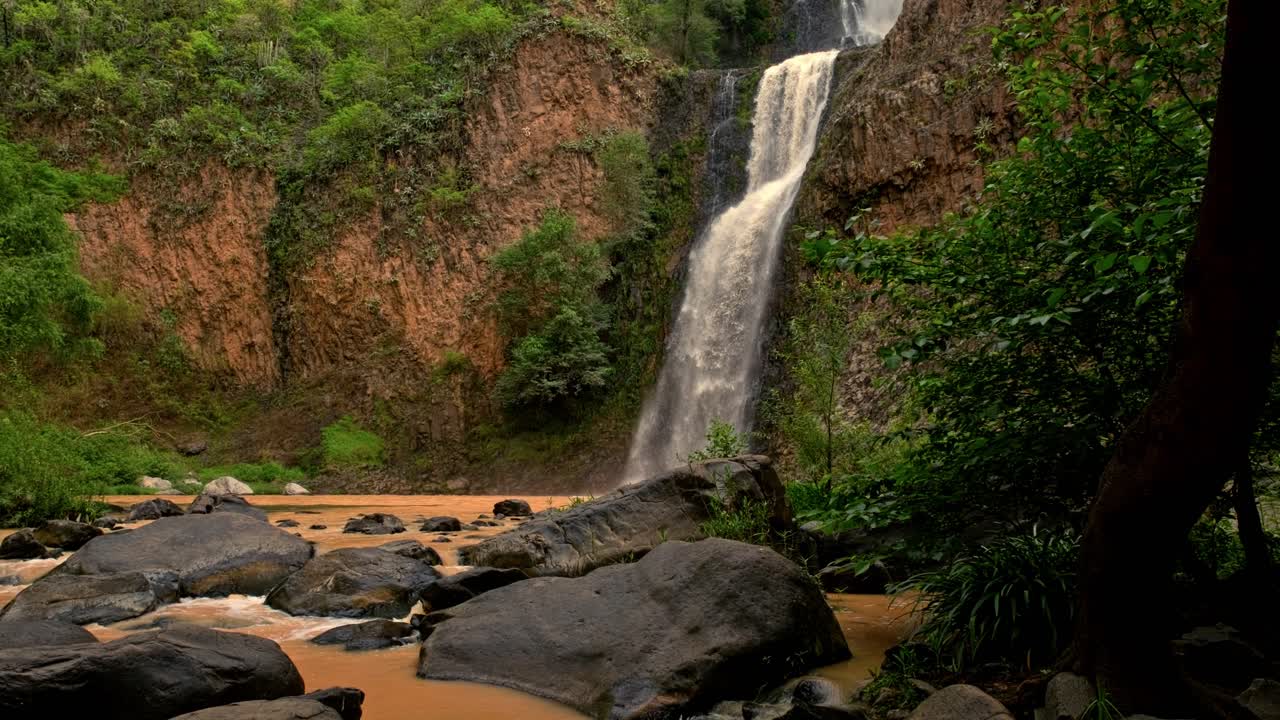 Lush waterfall cascading over rocks in a forest setting - Free Stock Video