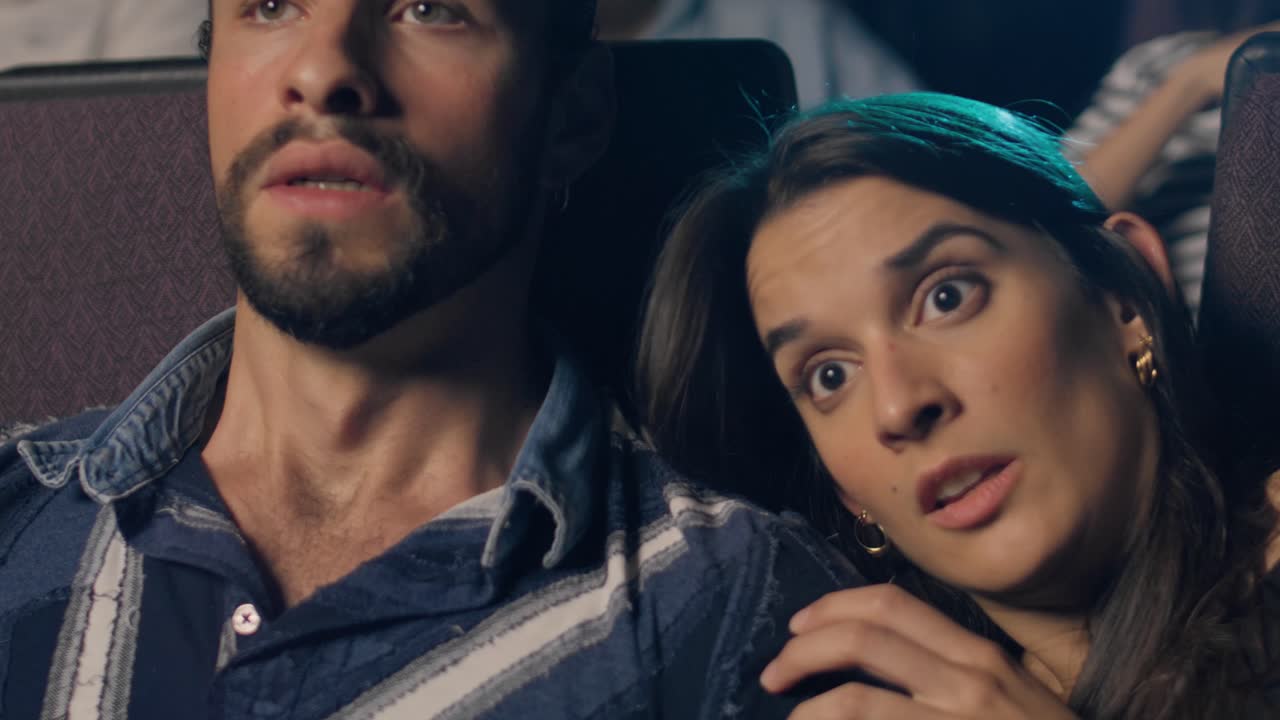 Woman asleep on man's shoulder in movie theater seats - Free Stock Video