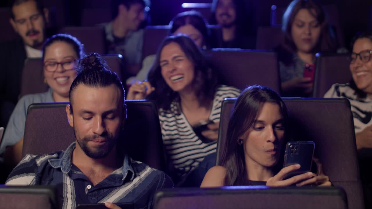 People watching a movie in a theater while using phones - Free Stock Video