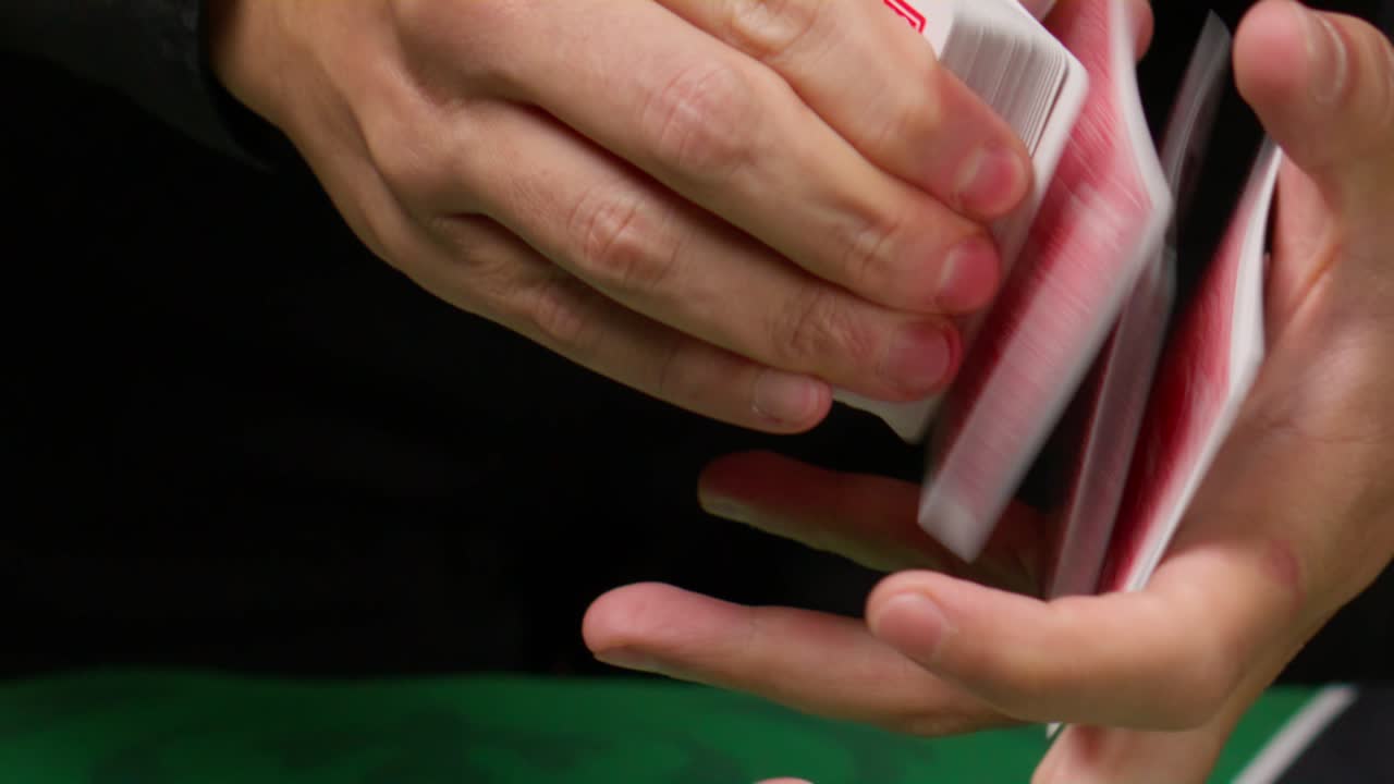 Person shuffling playing cards over green table - Free Stock Video