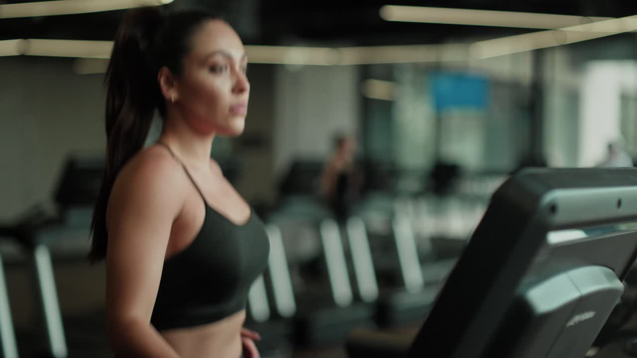 Woman jogging on a treadmill in a gym setting - Free Stock Video