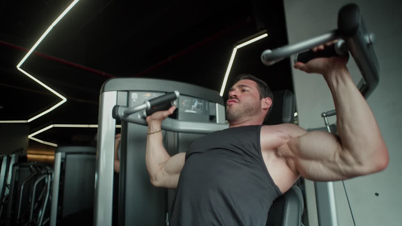 Man working out on a shoulder machine at the gym - Free Stock Video