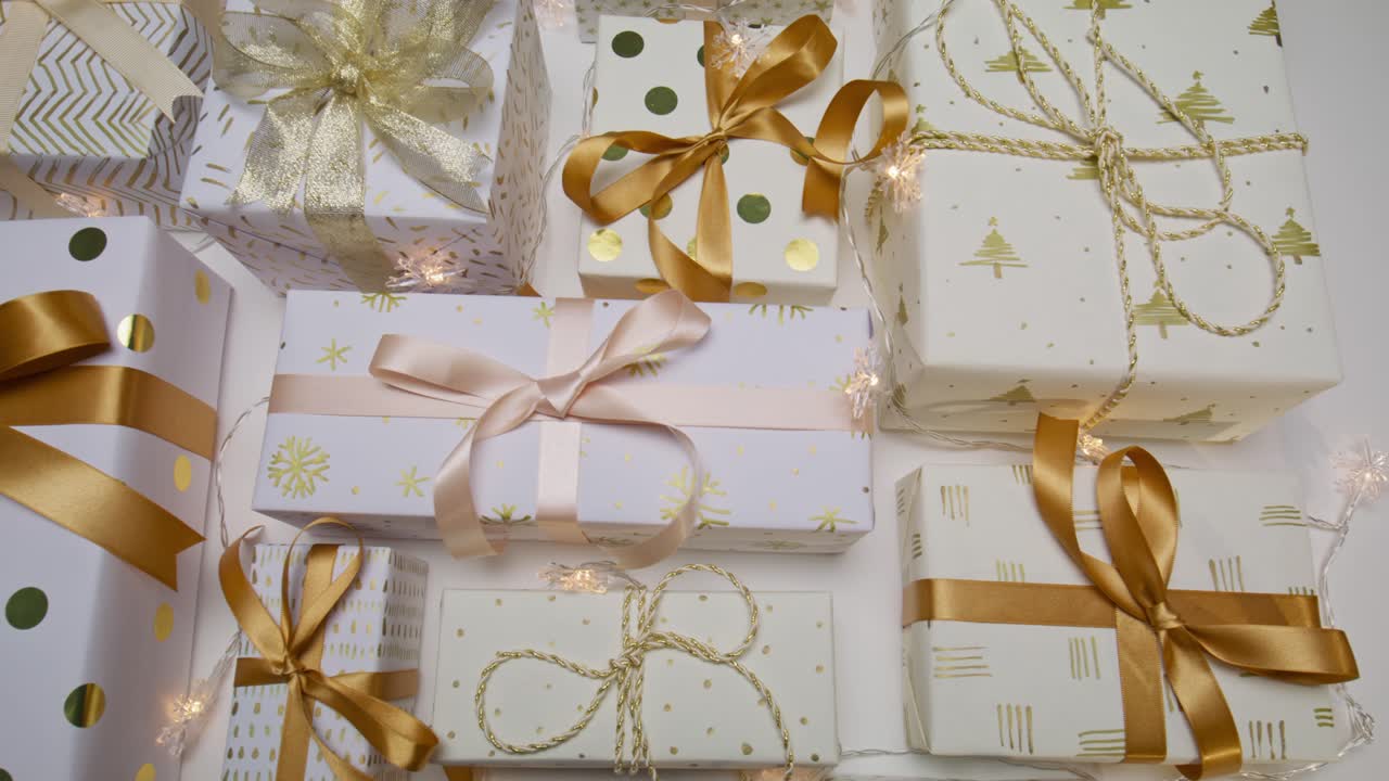 An Array of elegant christmas presents wrapped in white and gold with ...
