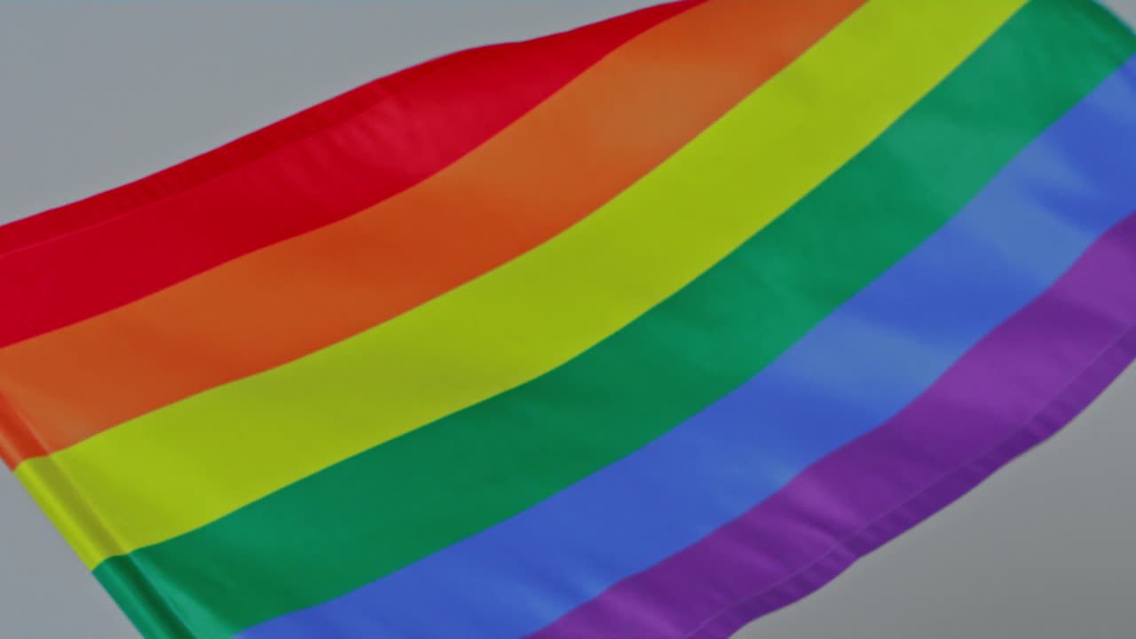 Original LGBTQ colorful pride flag waving with the wind over a gray ...