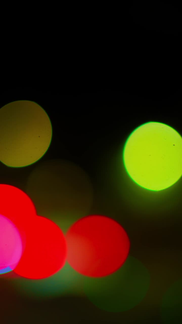 Vertical video scene of bokeh lights in different colors against a dark ...