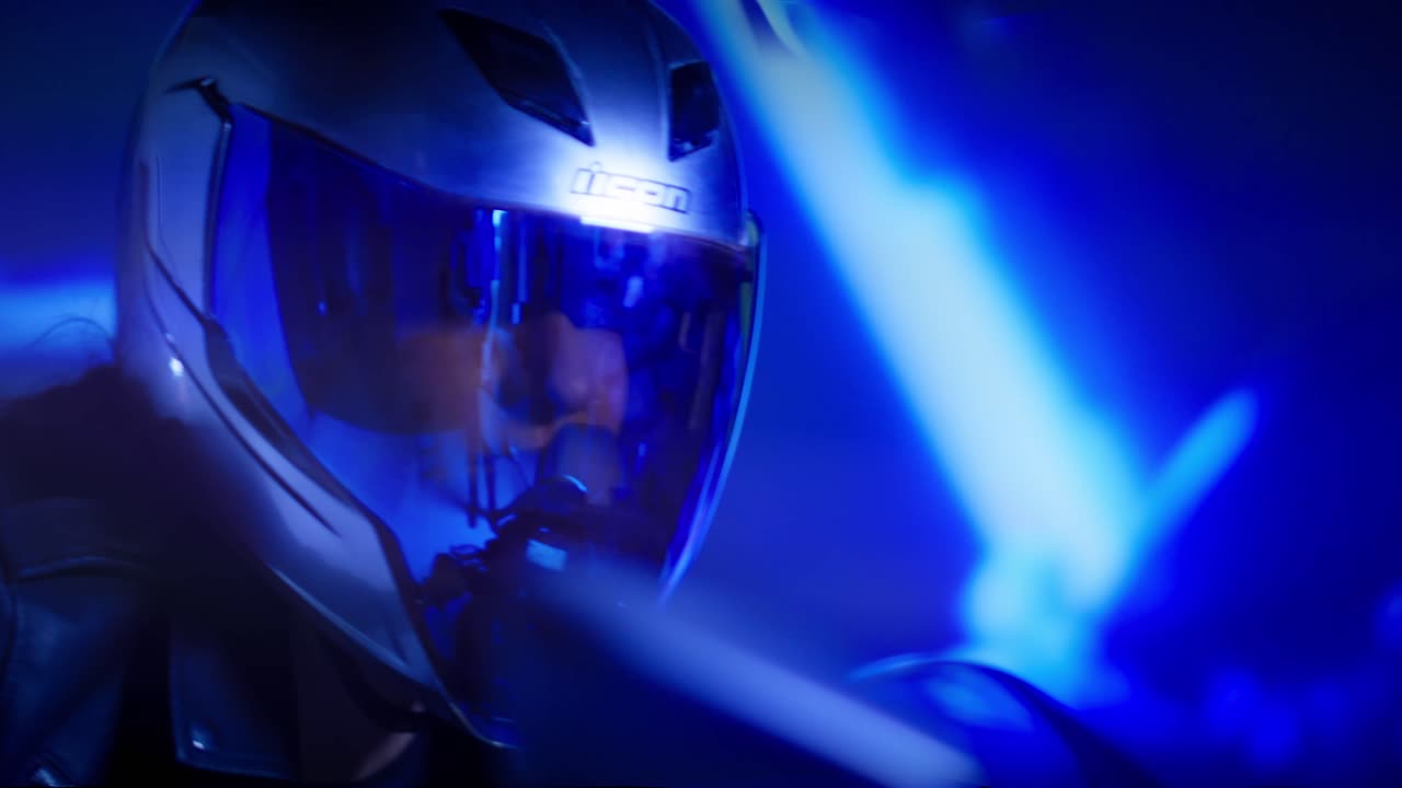 Close-up of a motorcyclist wearing a reflective silver helmet, driving ...