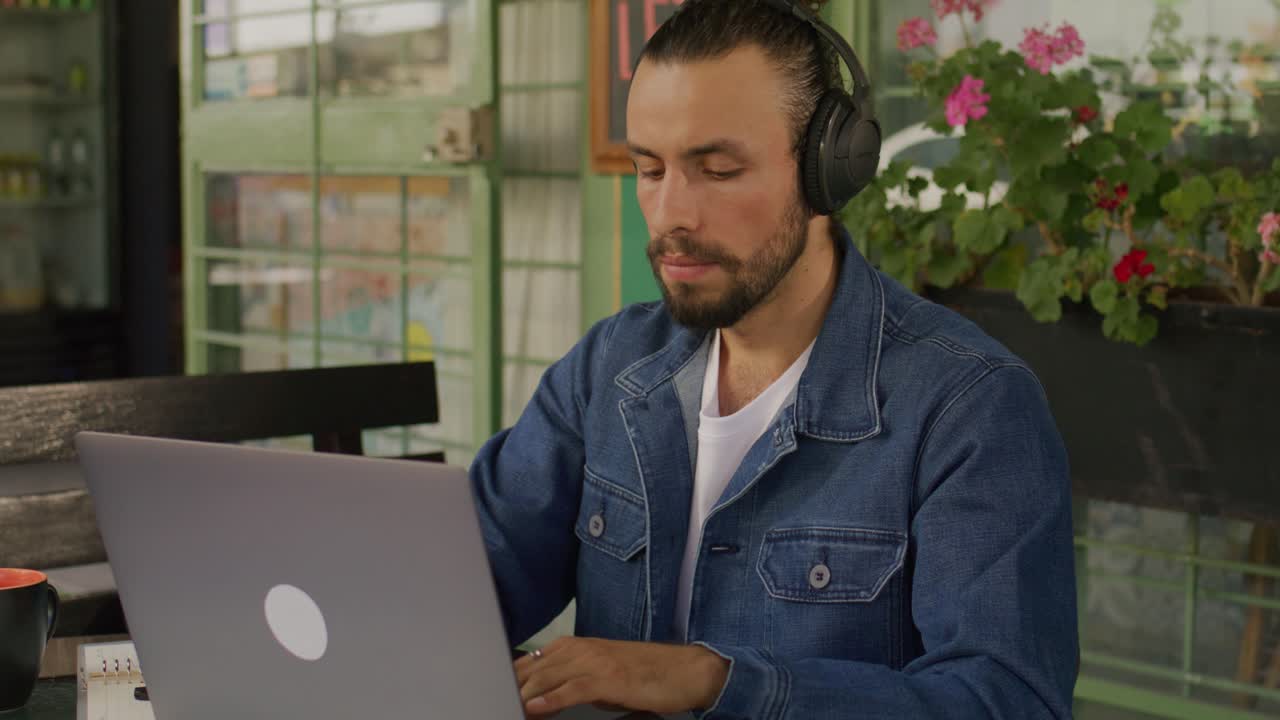 A young man vibing to the music on his headphones while he works on a ...