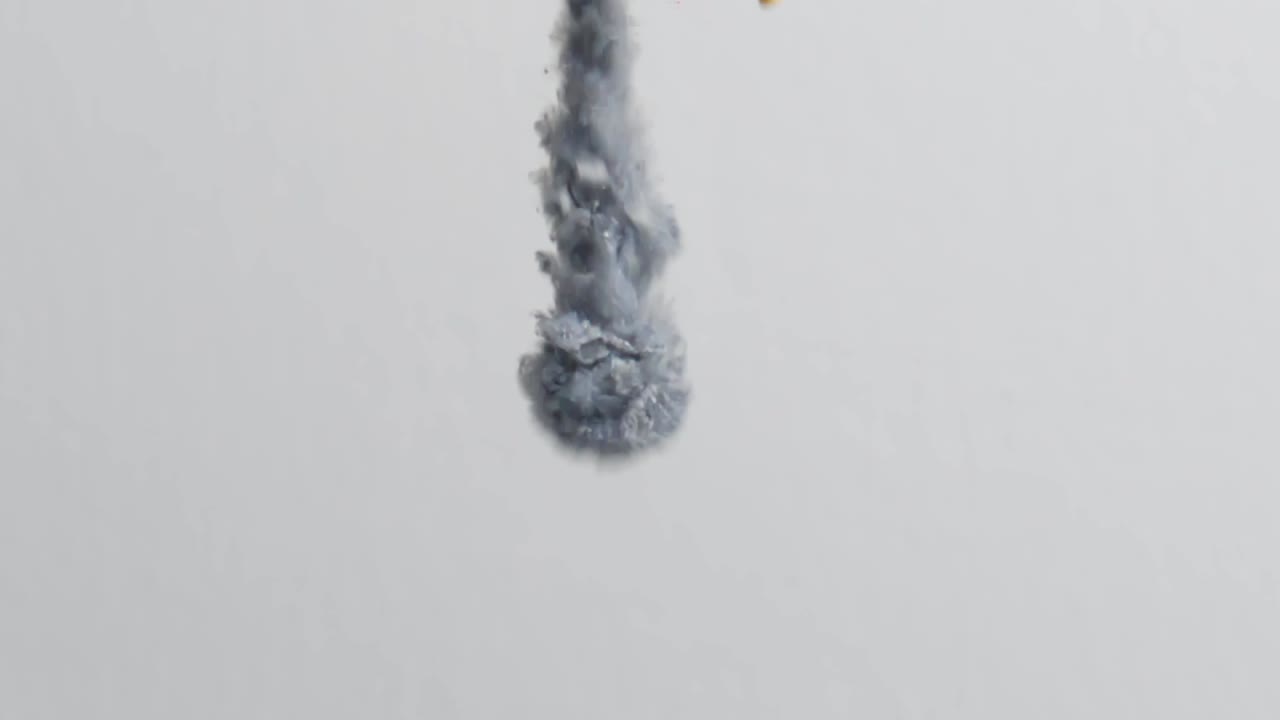 A continuous mix of grey and yellow smoke mix together in a transparent ...