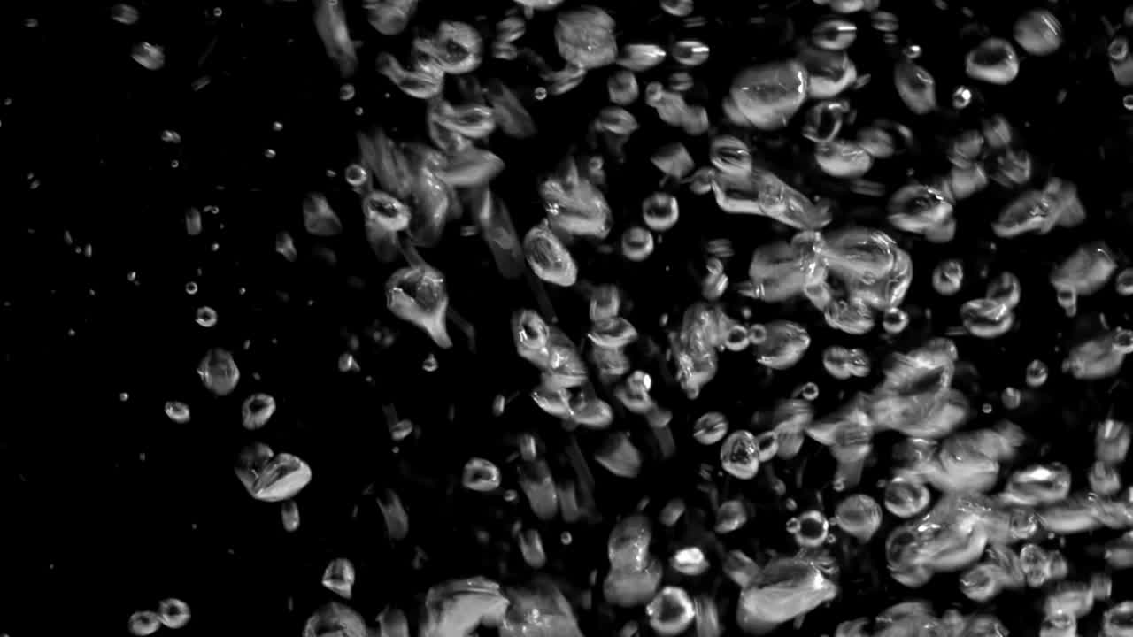 Water bubbles moving in a fast paced motion over a black background ...