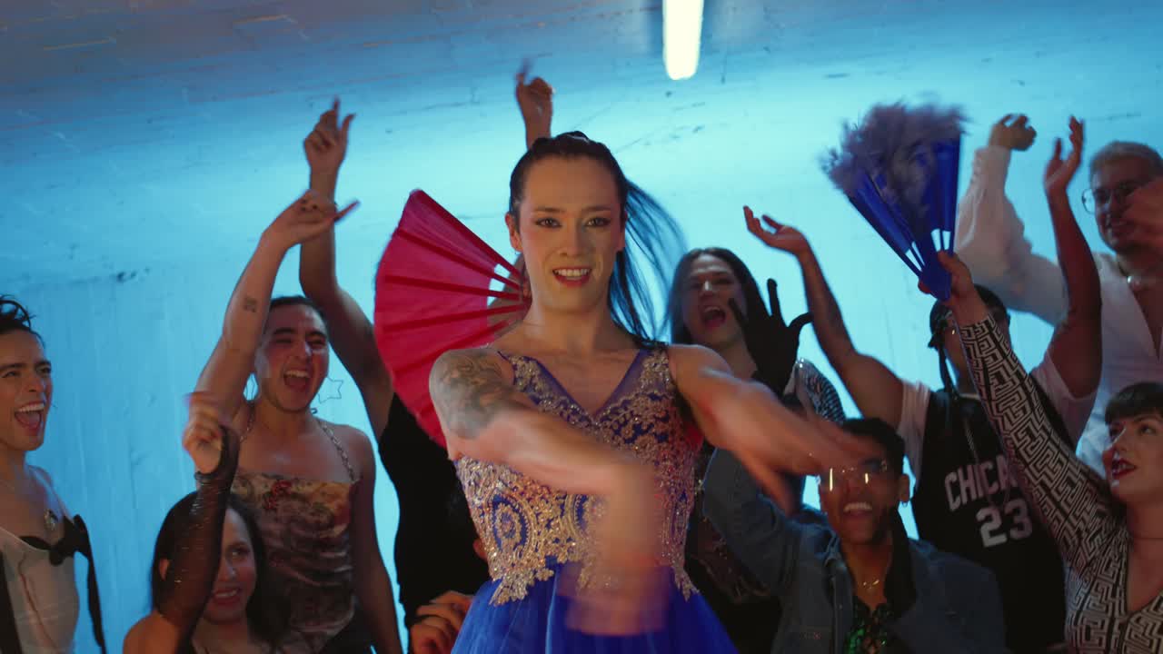 A young LGBTQ member with a blue skirt outfit dancing energetically ...