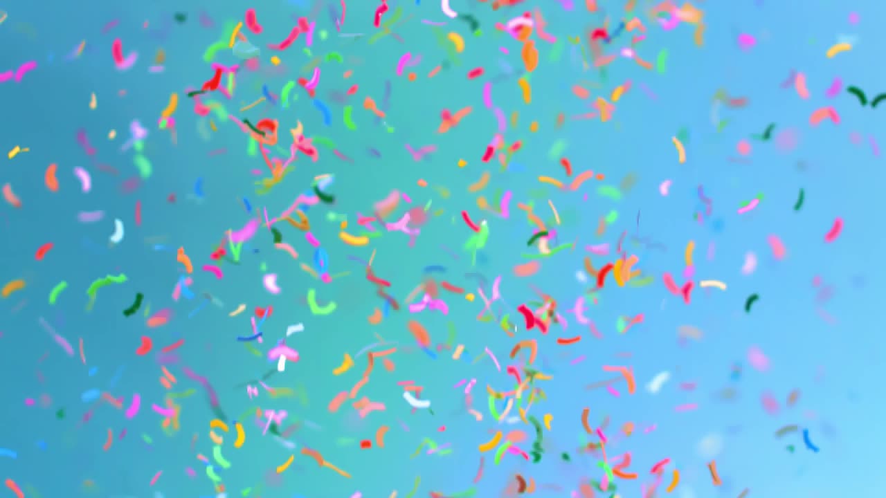 Multicolored confetti falling in slow motion over a blue background ...