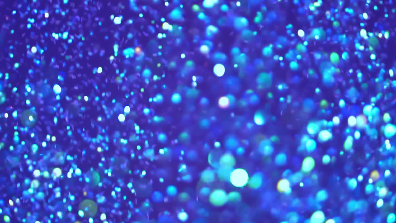 Close up shot of shiny blue confetti falling down in slow motion ...