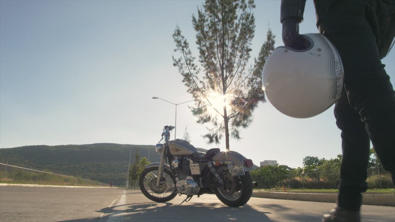 Man in biker gear approaches stationary motorcycle - Free Stock Video