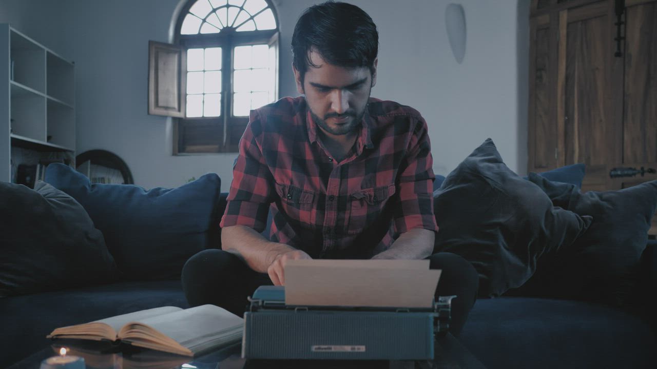 Man typing on a typewriter sitting in a room - Free Stock Video