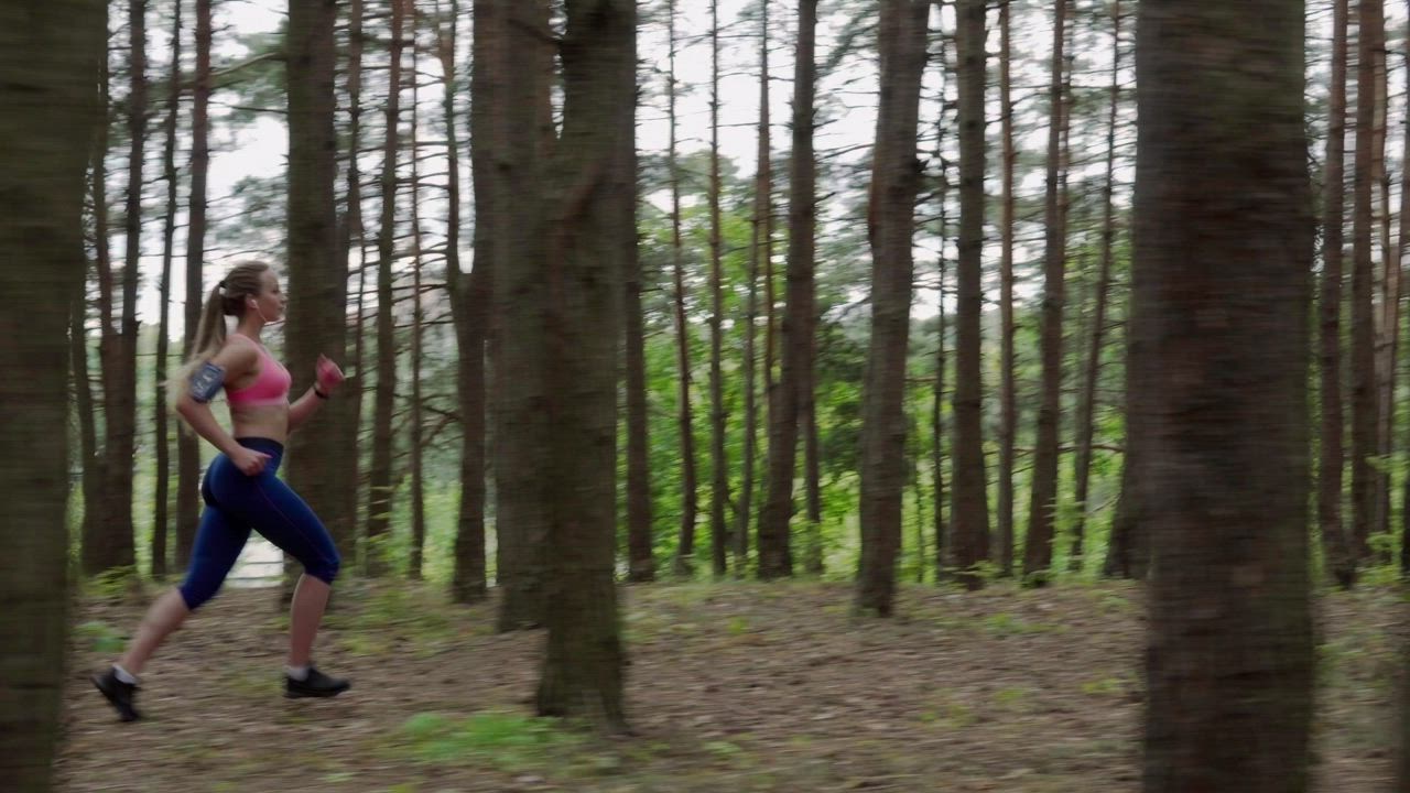 Woman running through the forest - Free Stock Video
