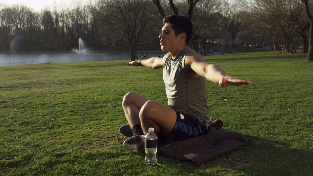 Man doing Yoga by a city lake - Free Stock Video