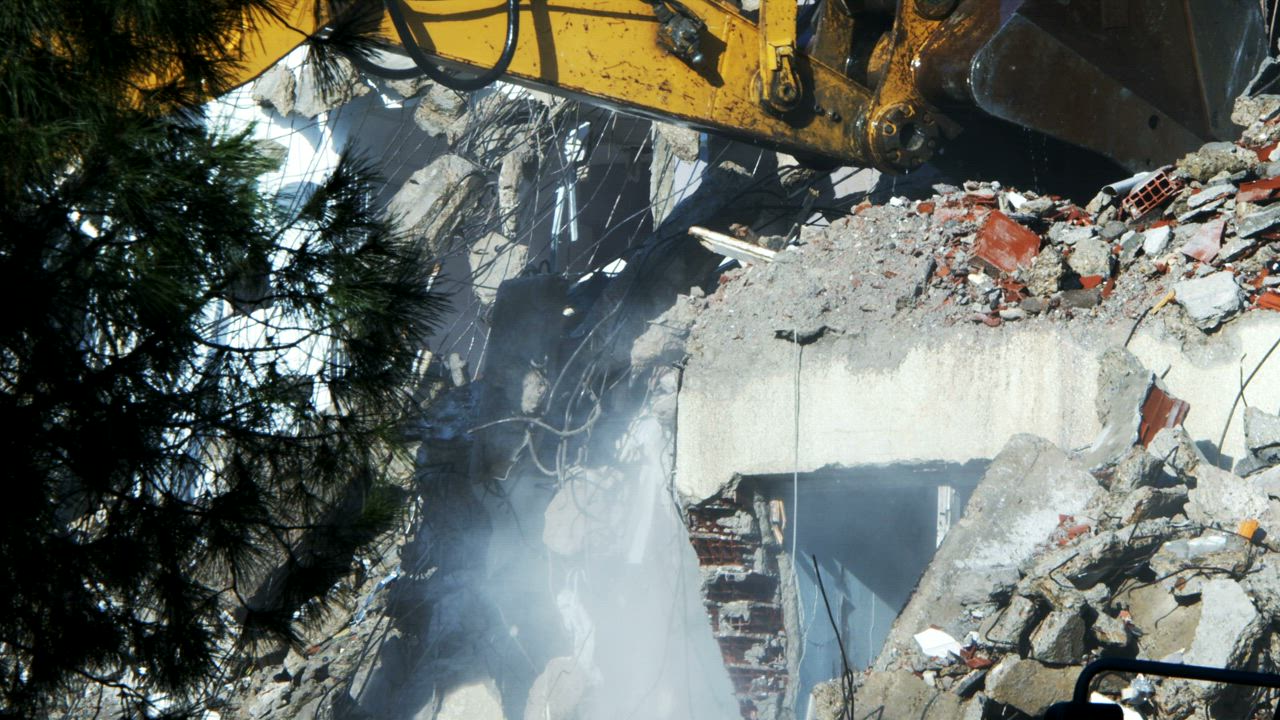 Bulldozer cleaning debris from a ruined building - Free Stock Video
