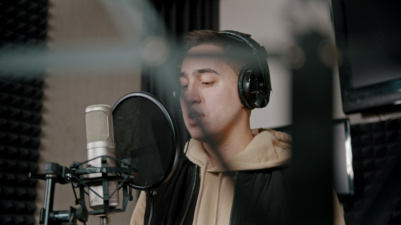 A rapper with headphones recording in the Studio - Free Stock Video