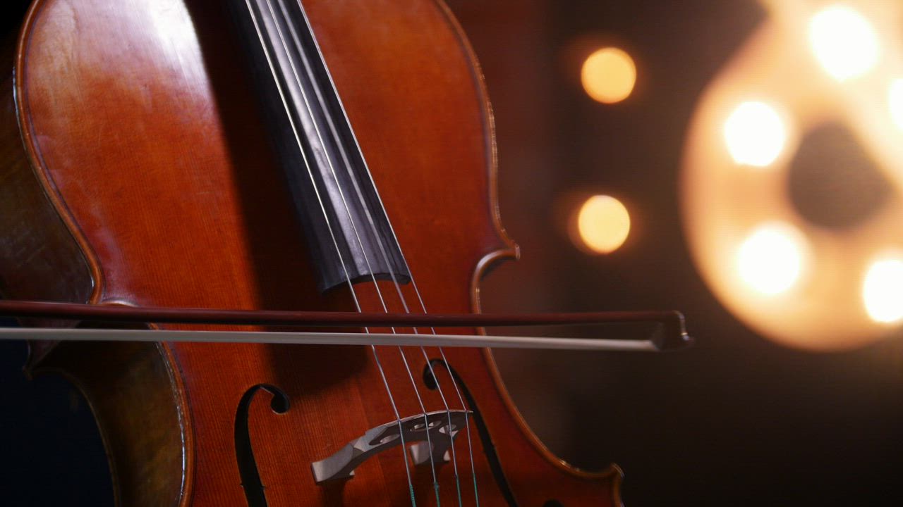 Playing the Cello with blurry lights in the background - Free Stock Video