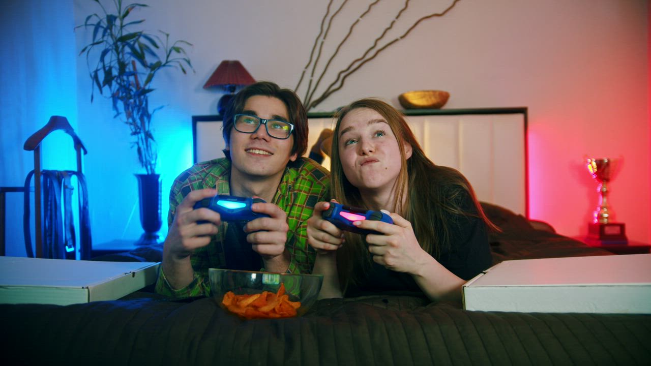 Young couple playing video games on the bed - Free Stock Video
