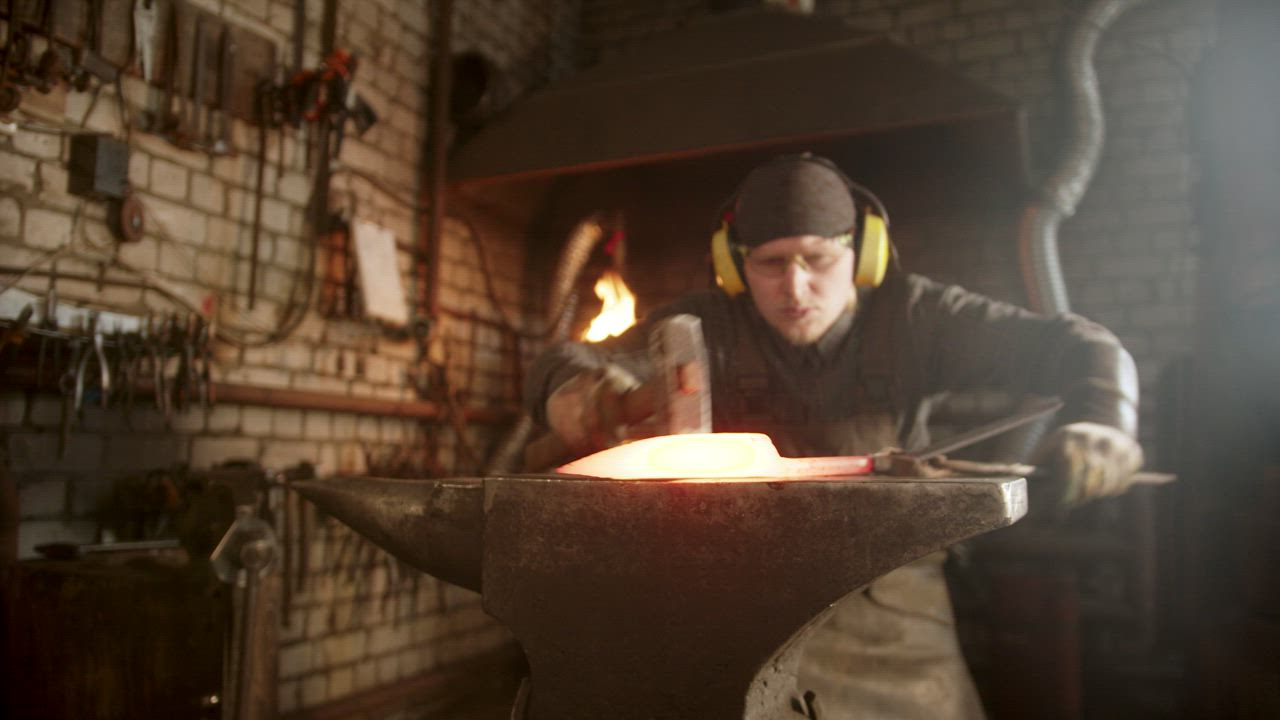 Blacksmith making a knife with a hammer on the forge - Free Stock Video