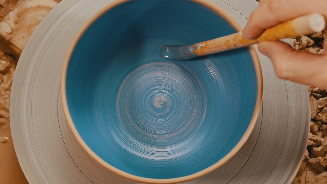 Painting a spinning pot blue using a brush - Free Stock Video