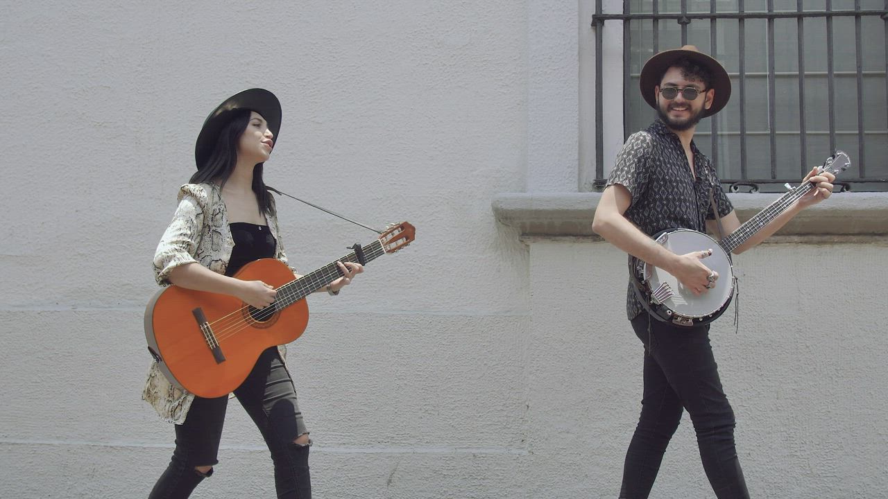 A man and a woman walking down the street playing music - Free Stock Video