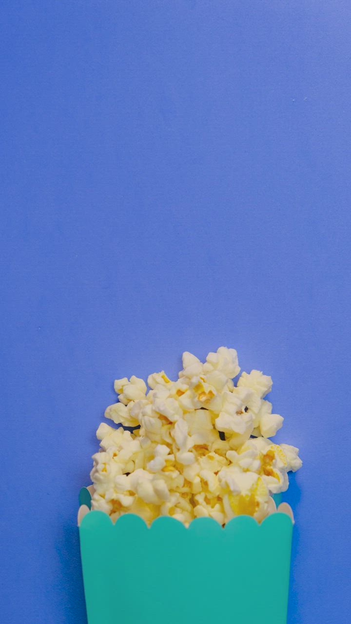 Popcorn scattered in stop motion on a blue background - Free Stock Video