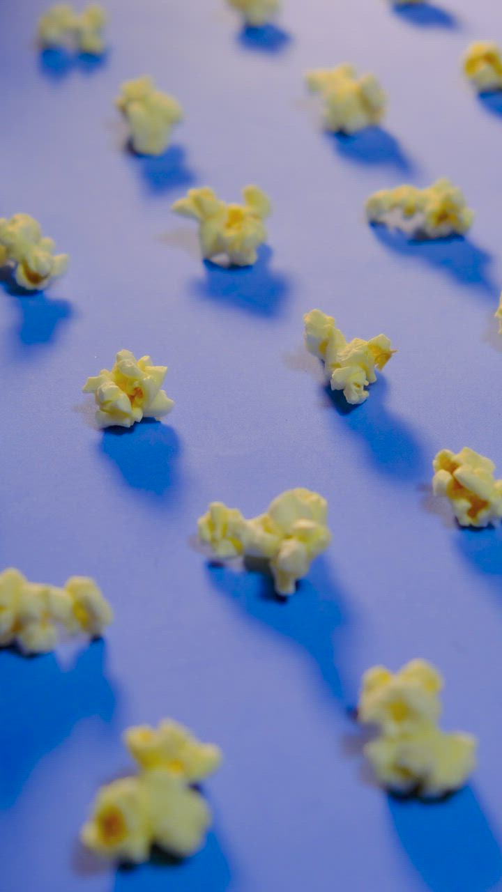 Popcorn on a blue surface changing size in stop motion - Free Stock Video