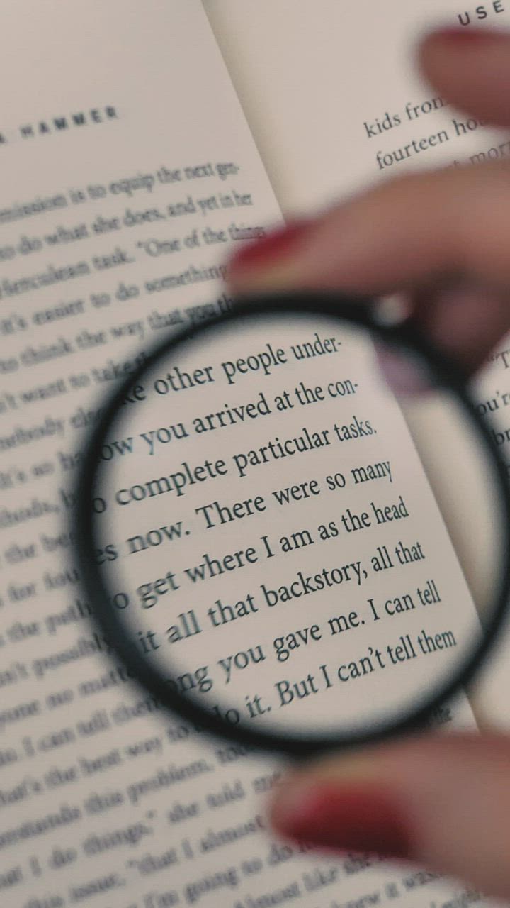 Woman reading a book helped by a magnifying glass - Free Stock Video