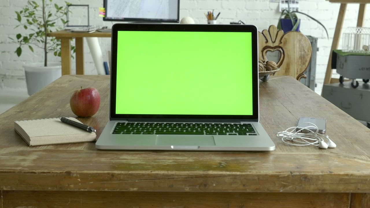 Laptop with a green screen over the table - Free Stock Video