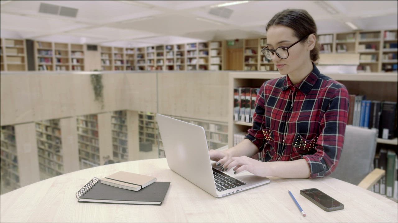 Girl typing on laptop computer in the library - Free Stock Video