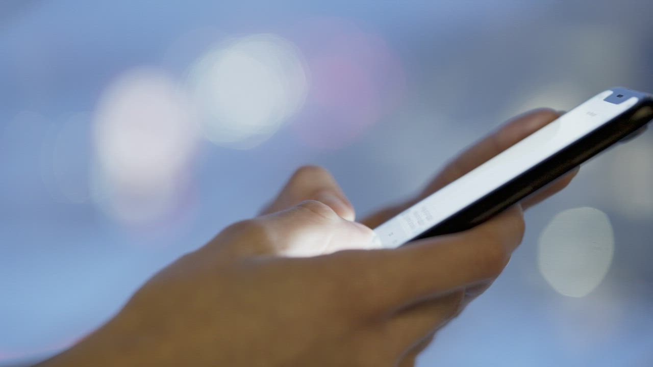 Hands texting on a mobile phone at night - Free Stock Video