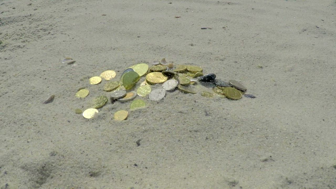 Coins buried in the sand - Free Stock Video