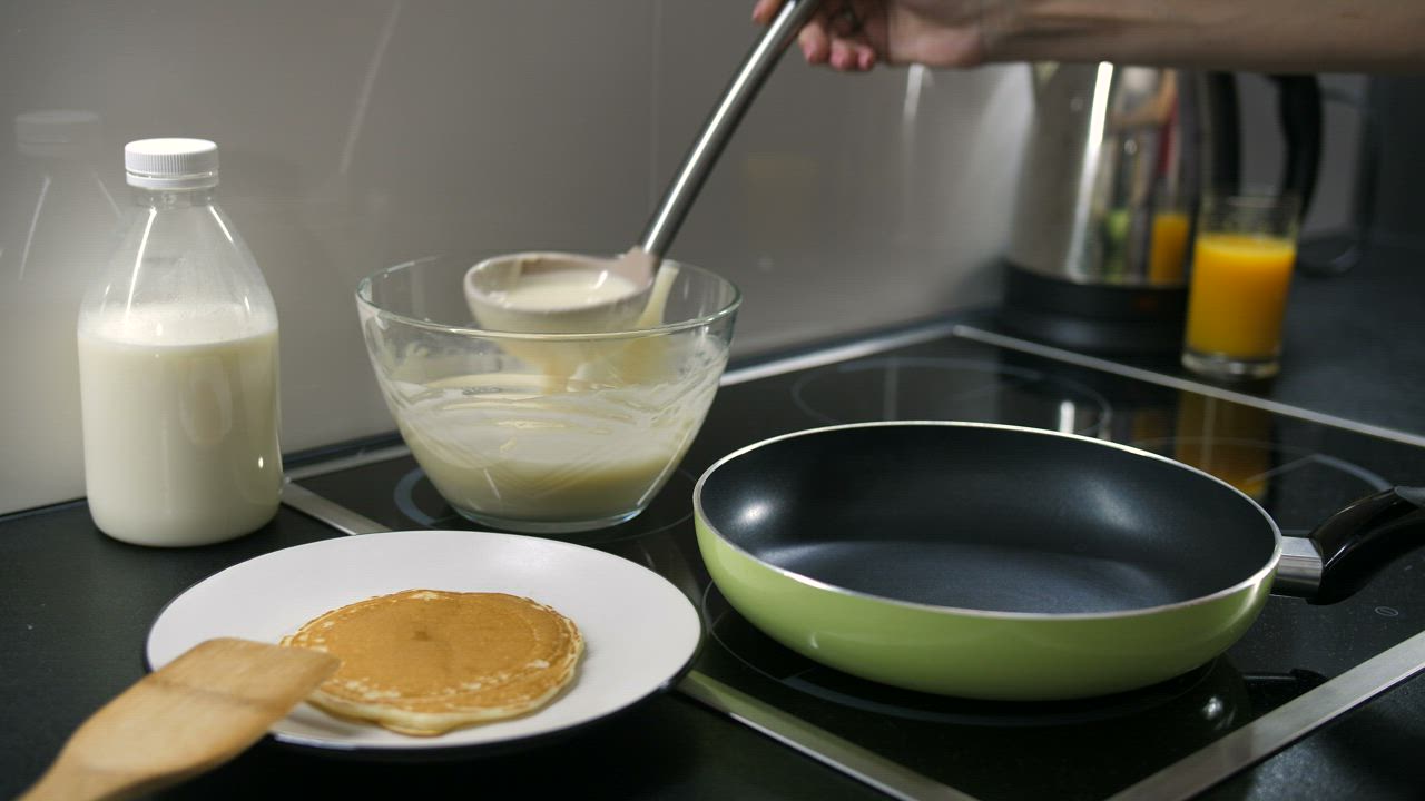 Pouring pancake mix into a pan - Free Stock Video