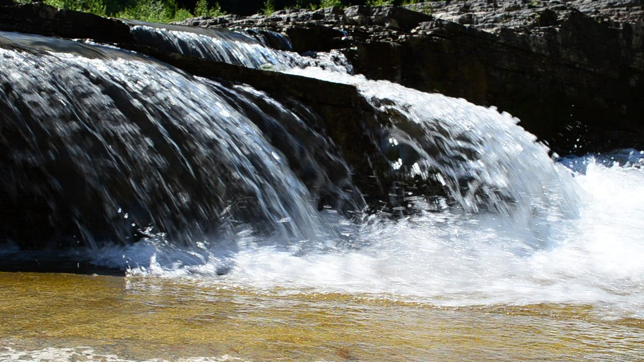 Clear river waters breaking over a rock - Free Stock Video