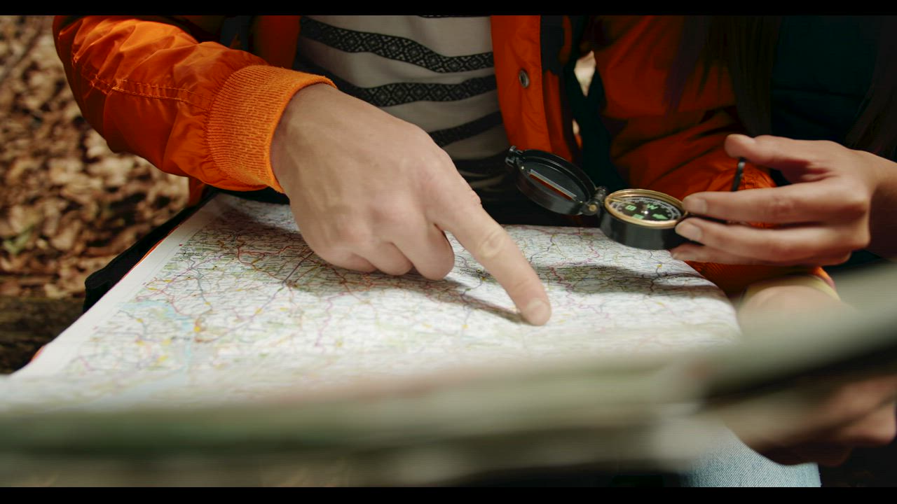 Closeup of hikers using map and compass in forest - Free Stock Video