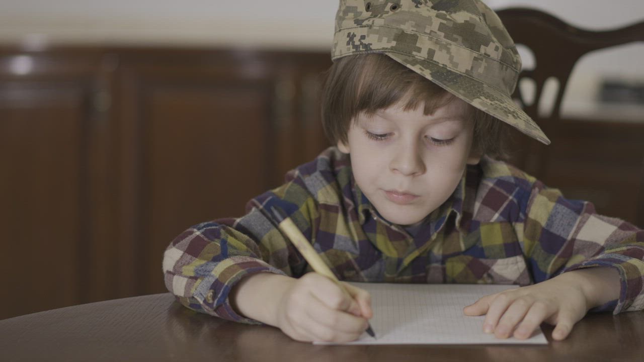 Little boy in Army hat writing letter to soldier - Free Stock Video