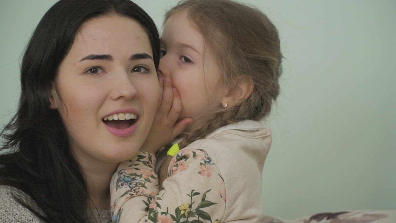 Little girl gossips in mom's ear - Free Stock Video