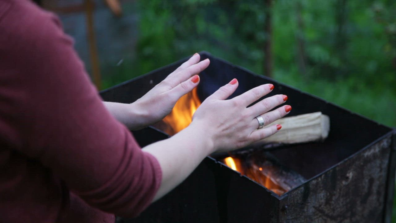 Warming her hands over a fire - Free Stock Video
