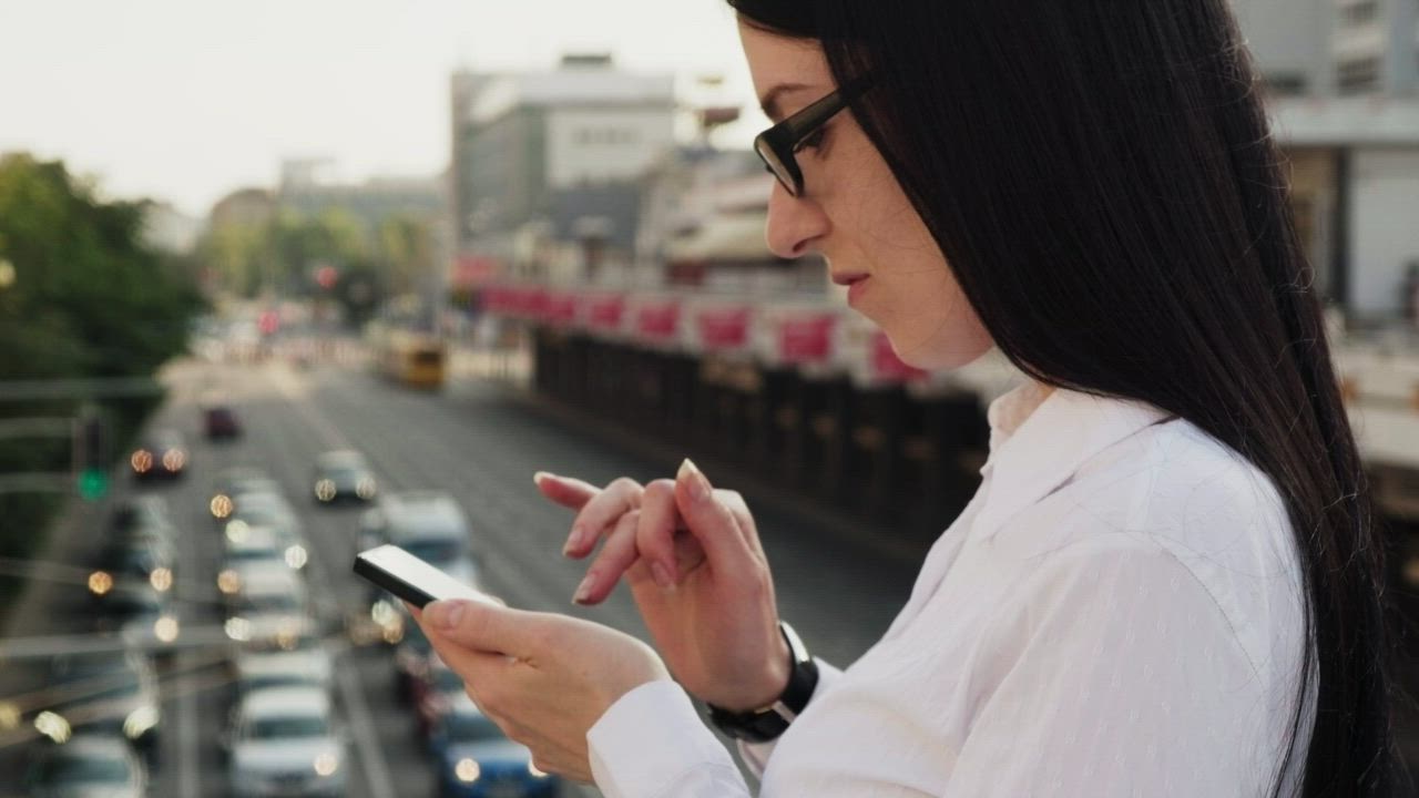 Checking her phone on a bridge - Free Stock Video