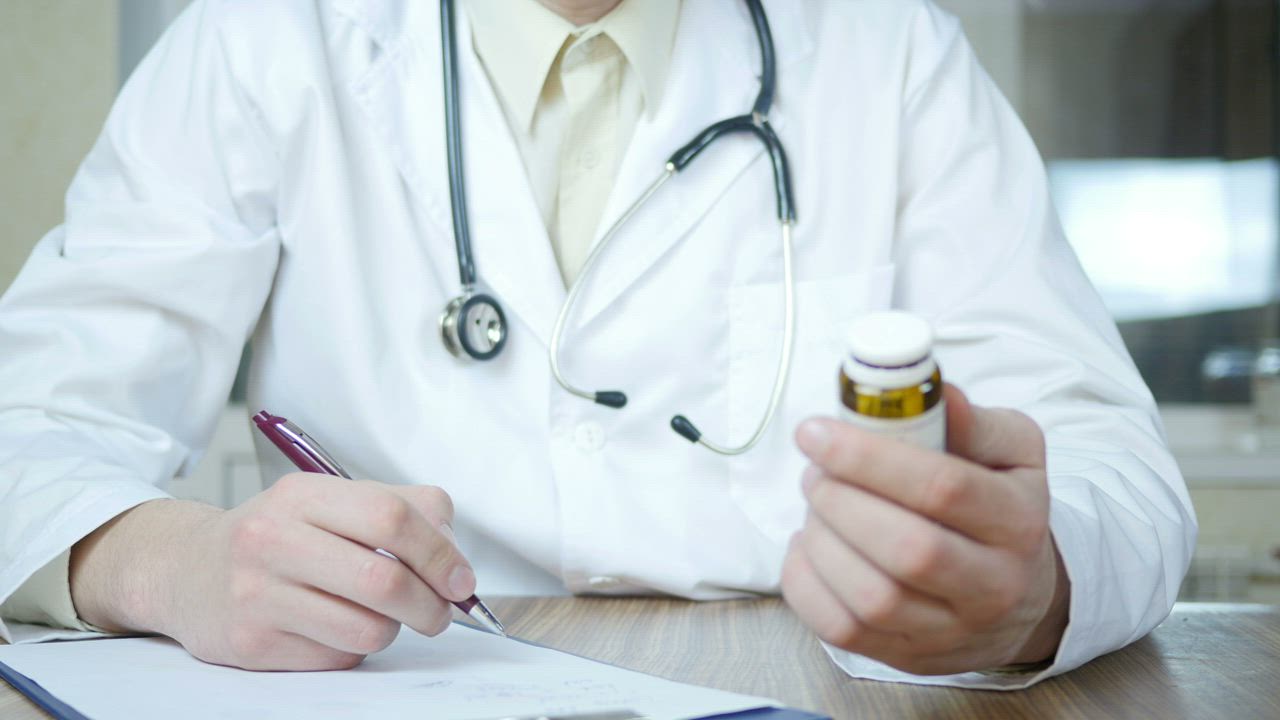 Doctor writing a prescription holding a medicine container - Free Stock ...