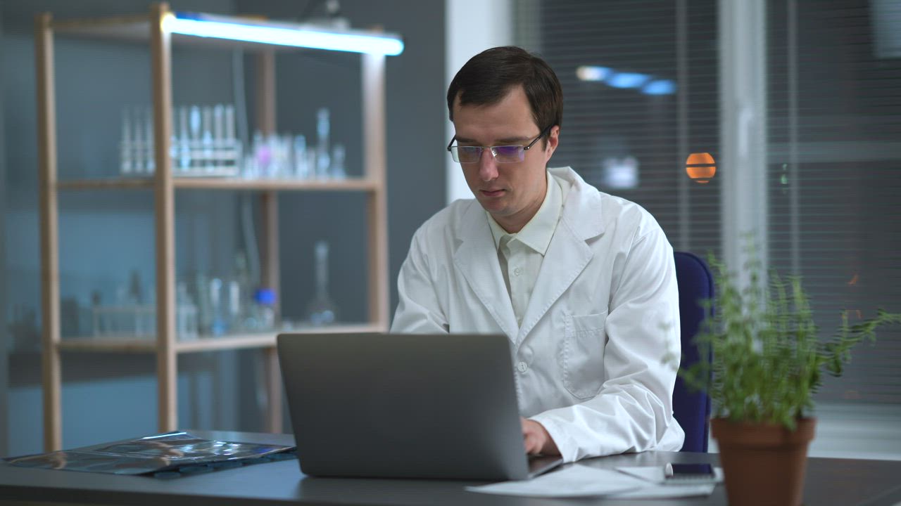 Doctor looking at an x-ray and working on the computer - Free Stock Video