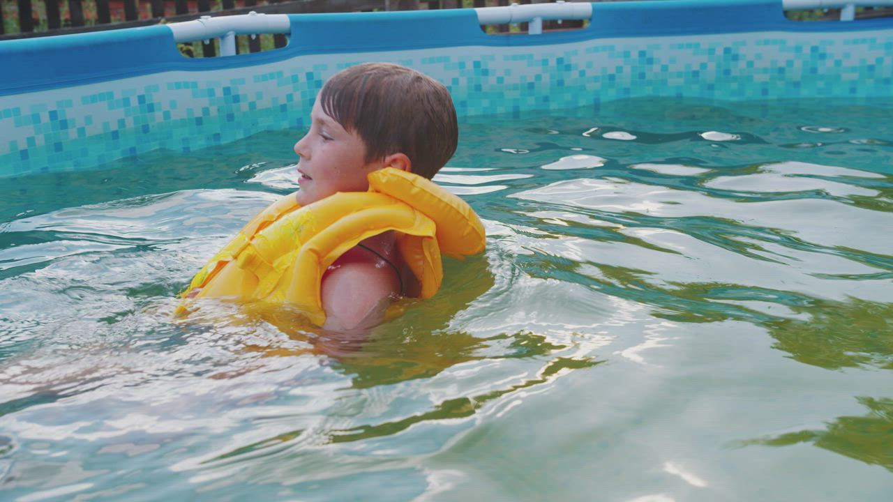 Young boy with inflatable vest swimming in the pool - Free Stock Video