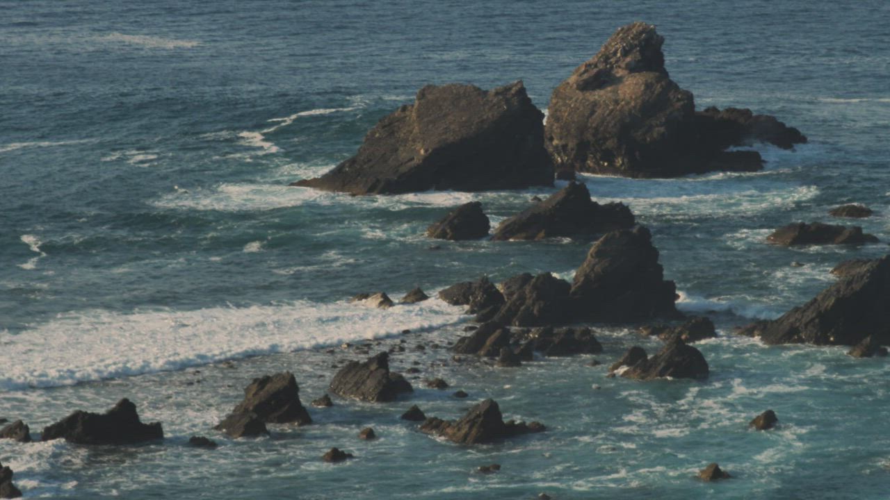 Waves hitting rocks on the beach - Free Stock Video